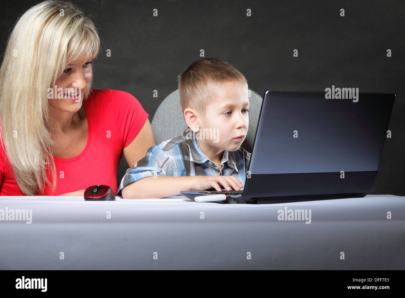 mother with son together looking on the laptop computer black ...