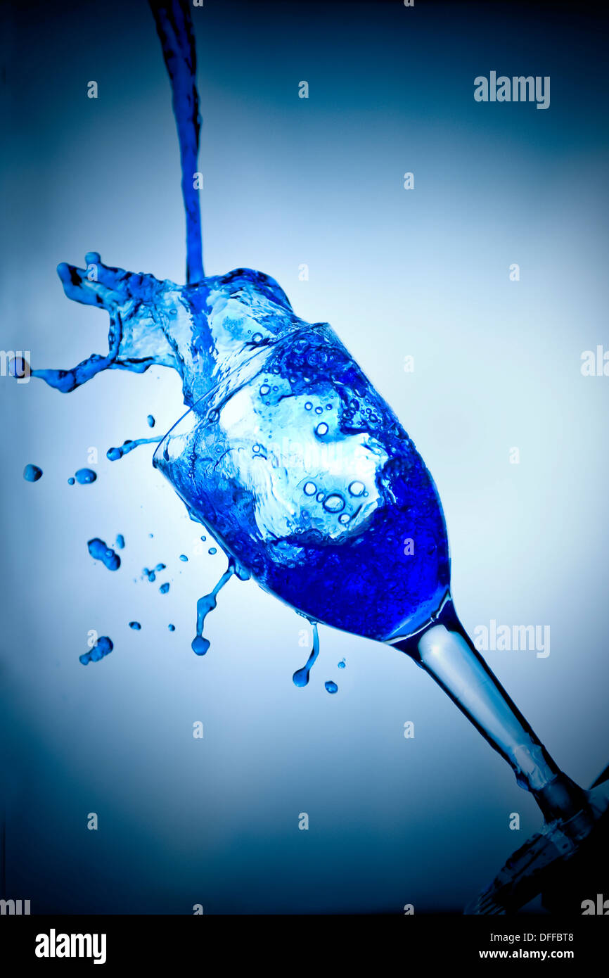 Blue liquid splashing out of a blue glass Stock Photo - Alamy