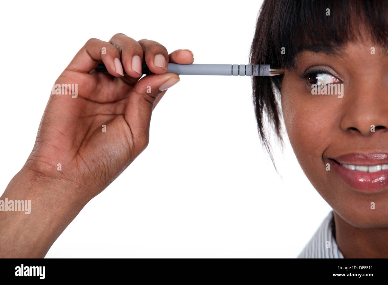 Attractive woman holding a pen to her head Stock Photo - Alamy