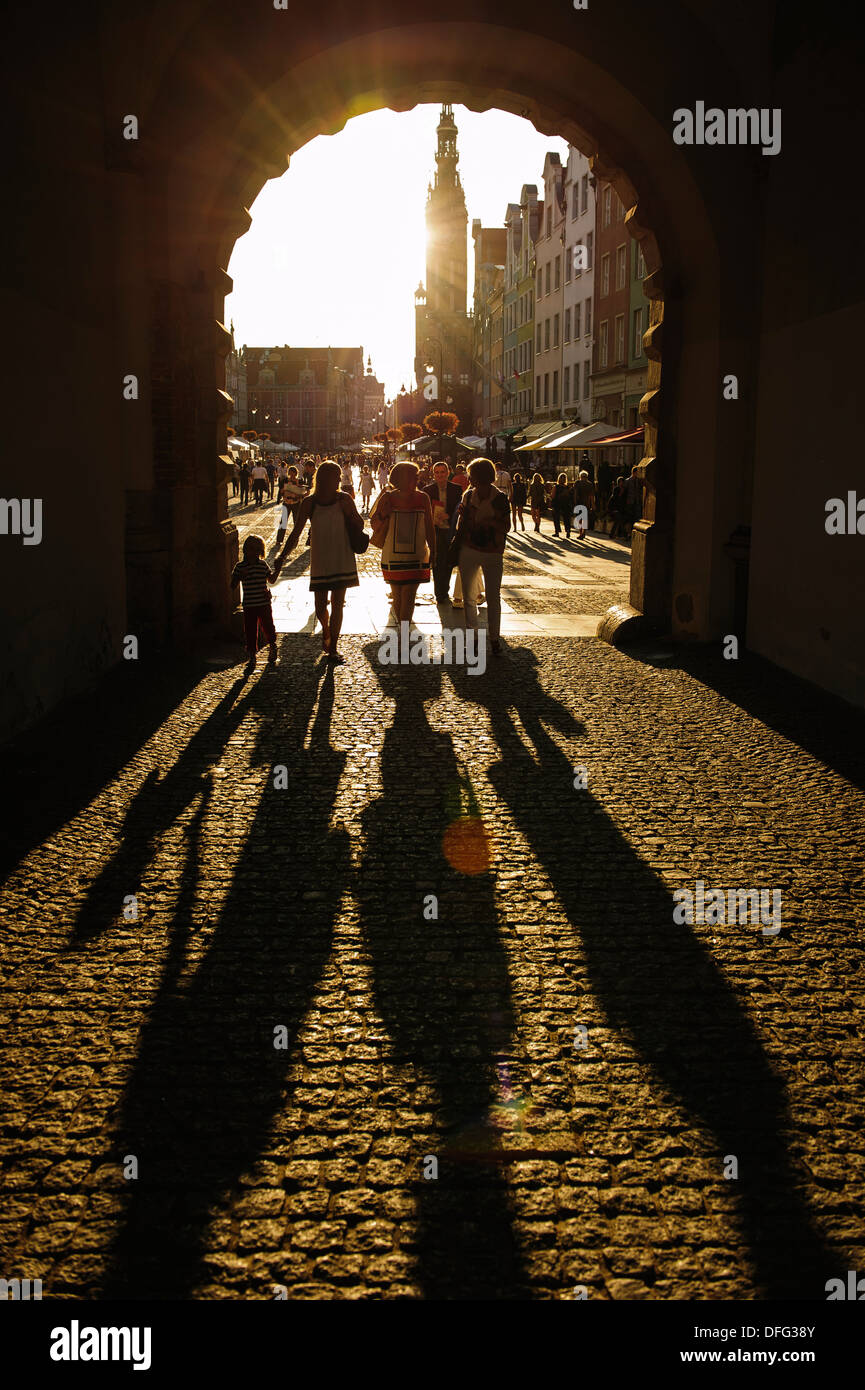 A group of people walking by the Green gate of Gdansk at sunset time ...