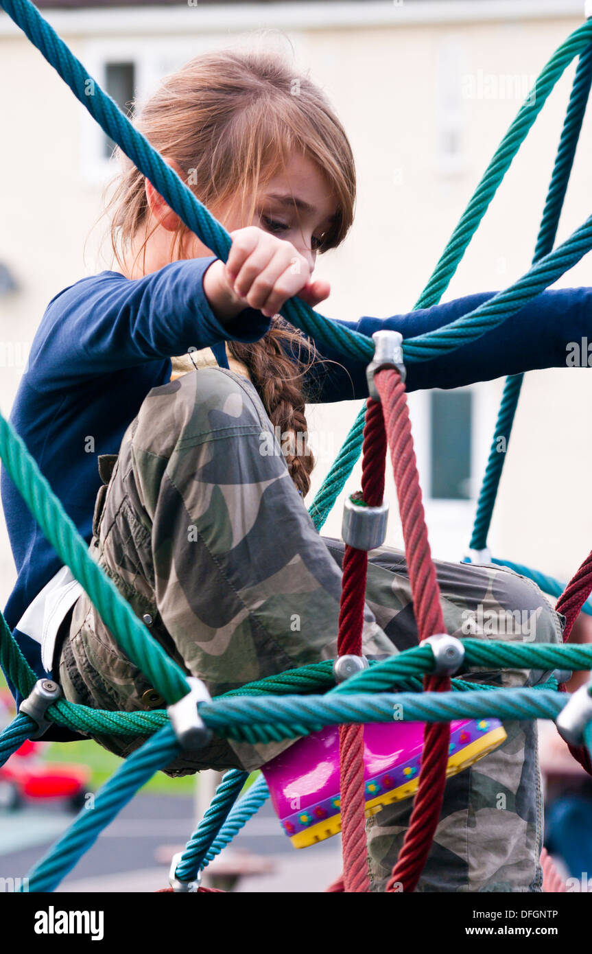 Little Girl Climbing Up A Rope Climbing Frame At A Childrens Playground ...