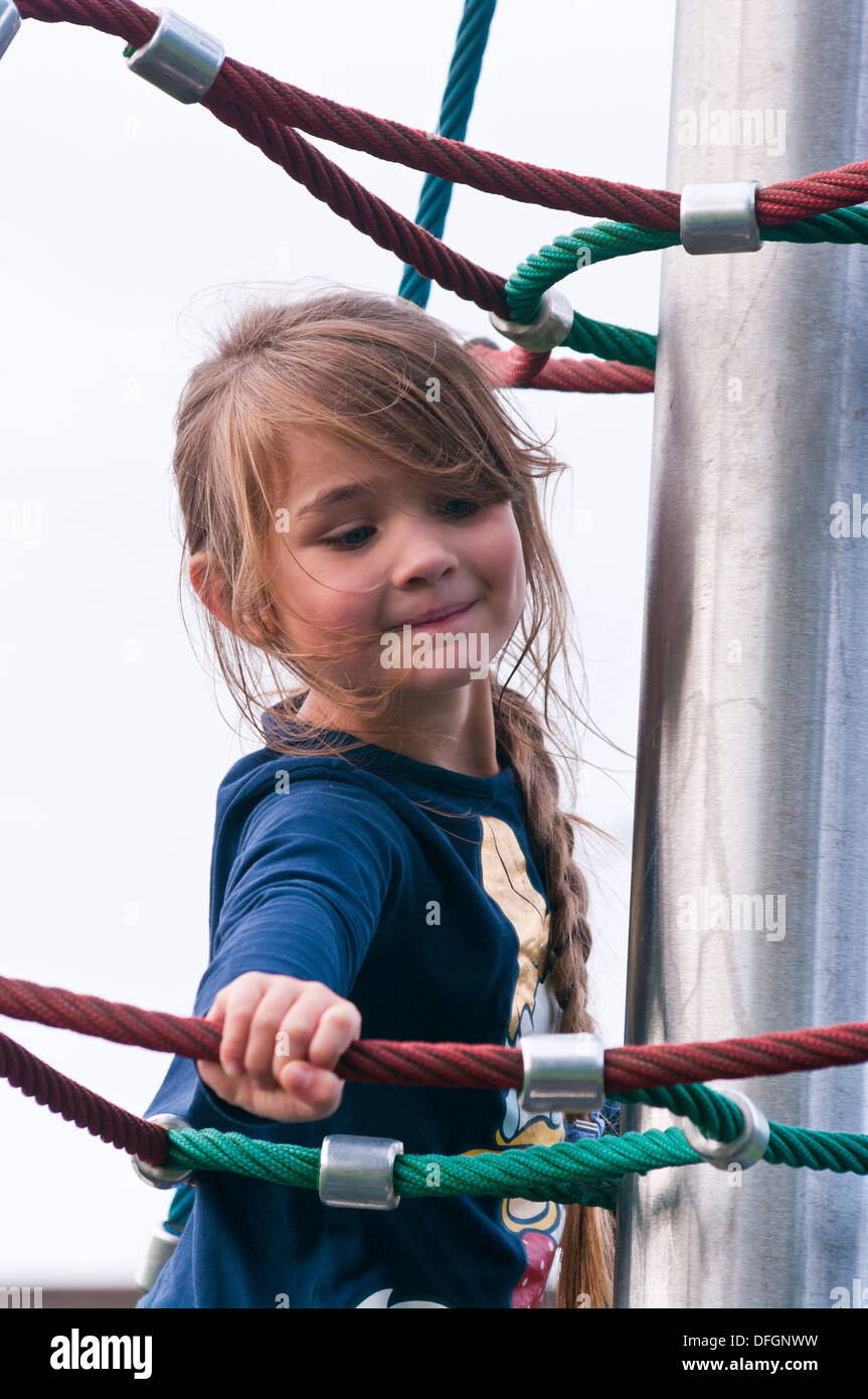 Little Girl Climbing Up A Rope Climbing Frame At A Childrens Playground ...
