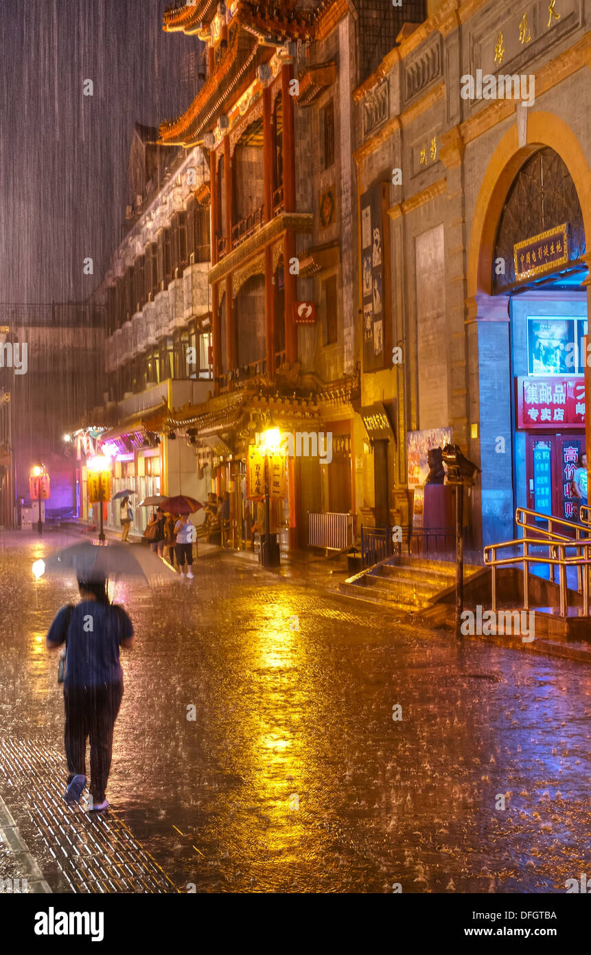 Woman walking under umbrella during rainy night in Beijing, China Stock ...