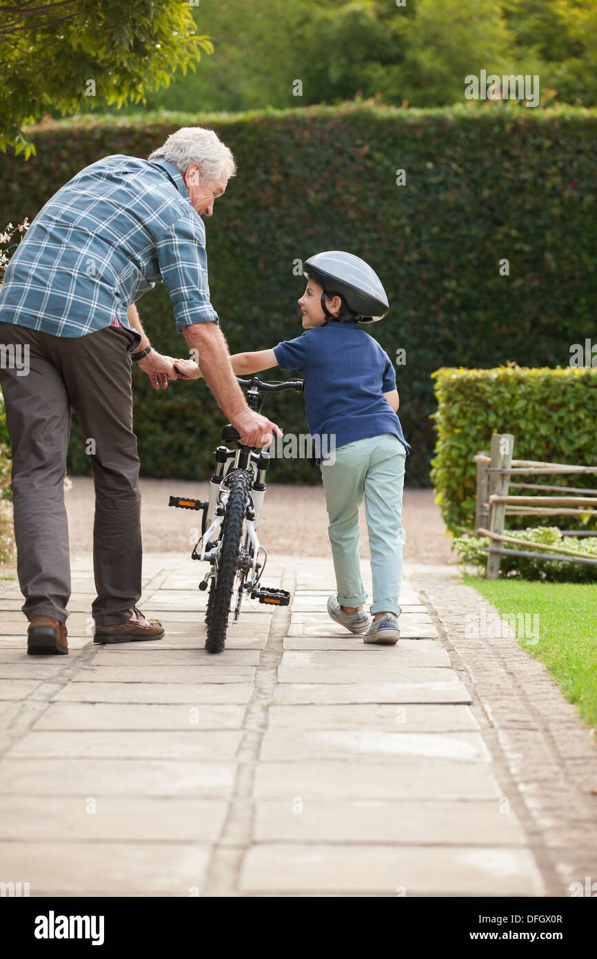 Grandfather and grandson pushing bicycle on sidewalk Stock Photo - Alamy