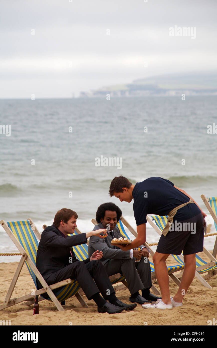wedding guests - two young men sitting in deckchairs being served food ... wedding guests - two young men sitting in deckchairs being served food ...