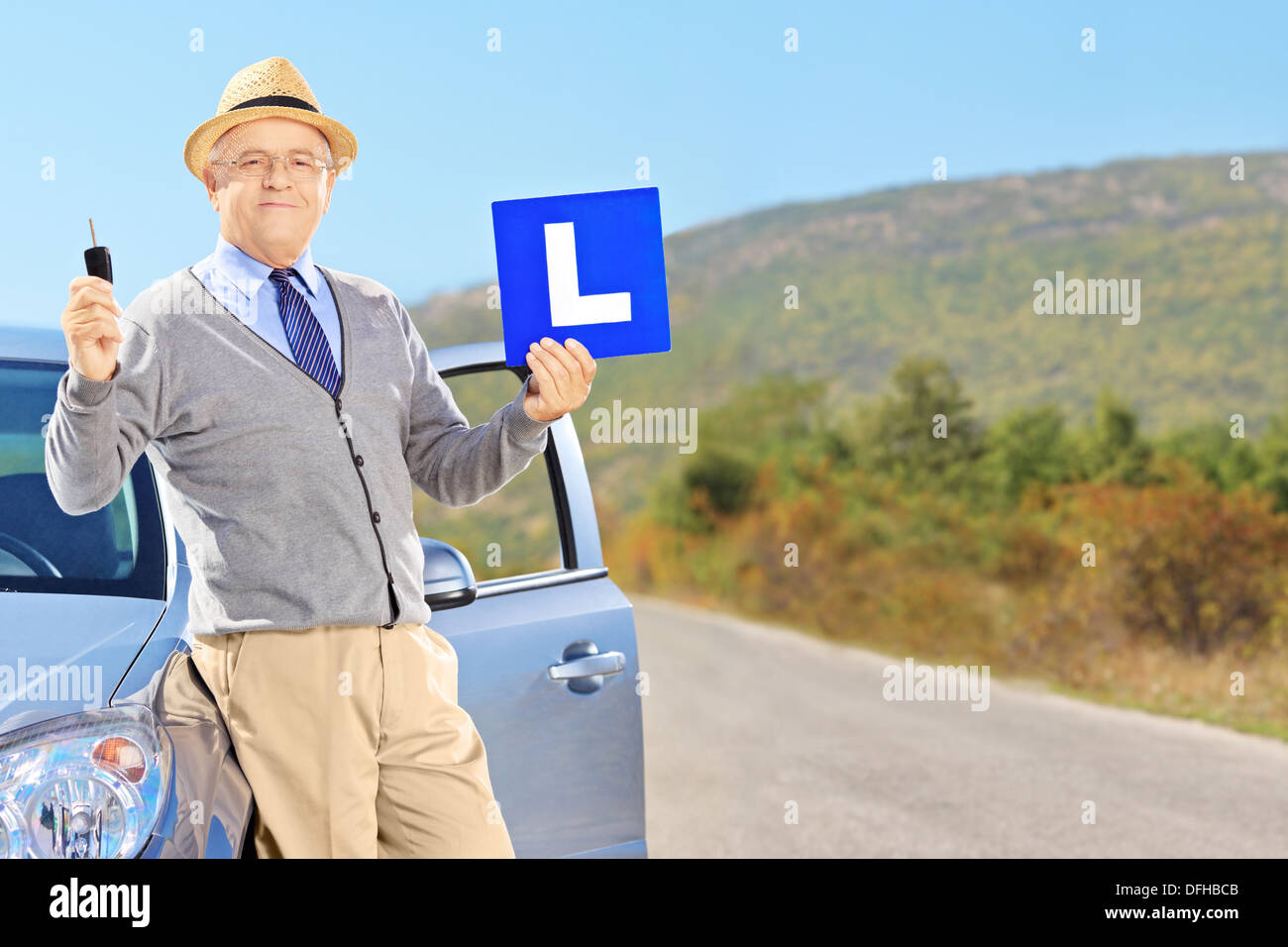 Senior man posing on his car, holding a L sign and car key after having ...