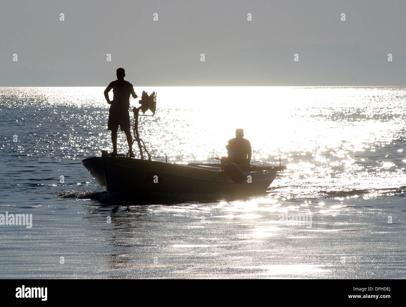 Boat sailing away at sundown Stock Photo - Alamy