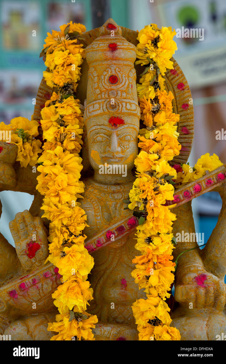 Stone Hindu goddess Saraswati statue and flowers. Andhra Pradesh, India ...