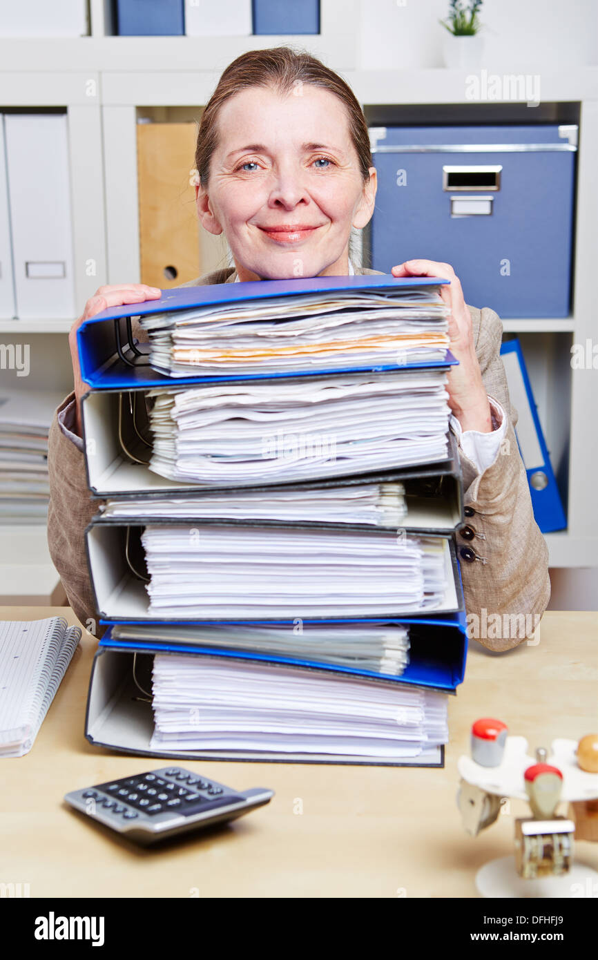 Smiling senior business woman with files on her desk in her office ...