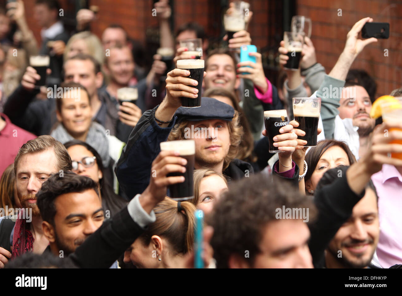 Image of hands in a crowd holding pints of Guinness in the air during ...