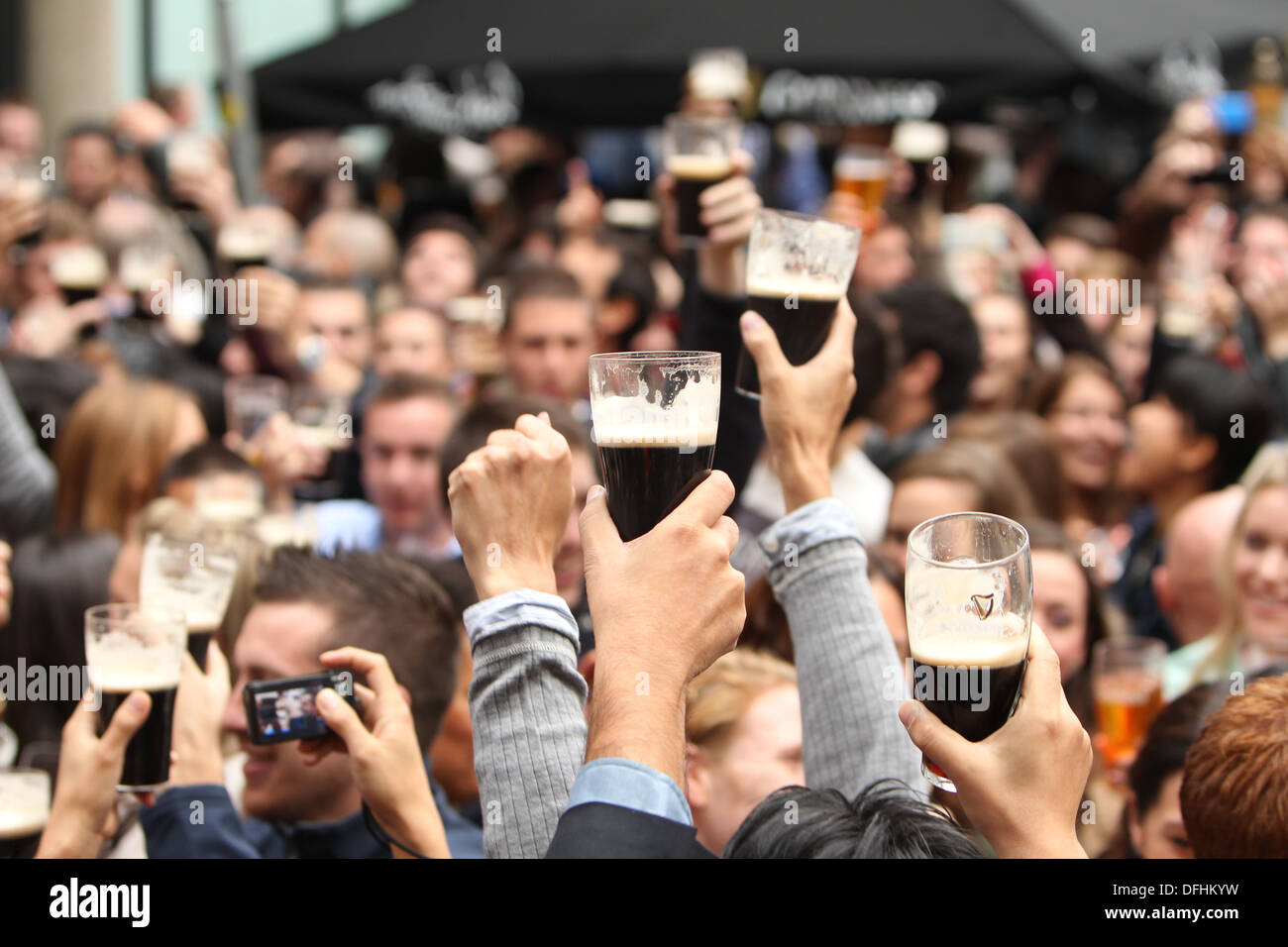Image of hands in a crowd holding pints of Guinness in the air during ...