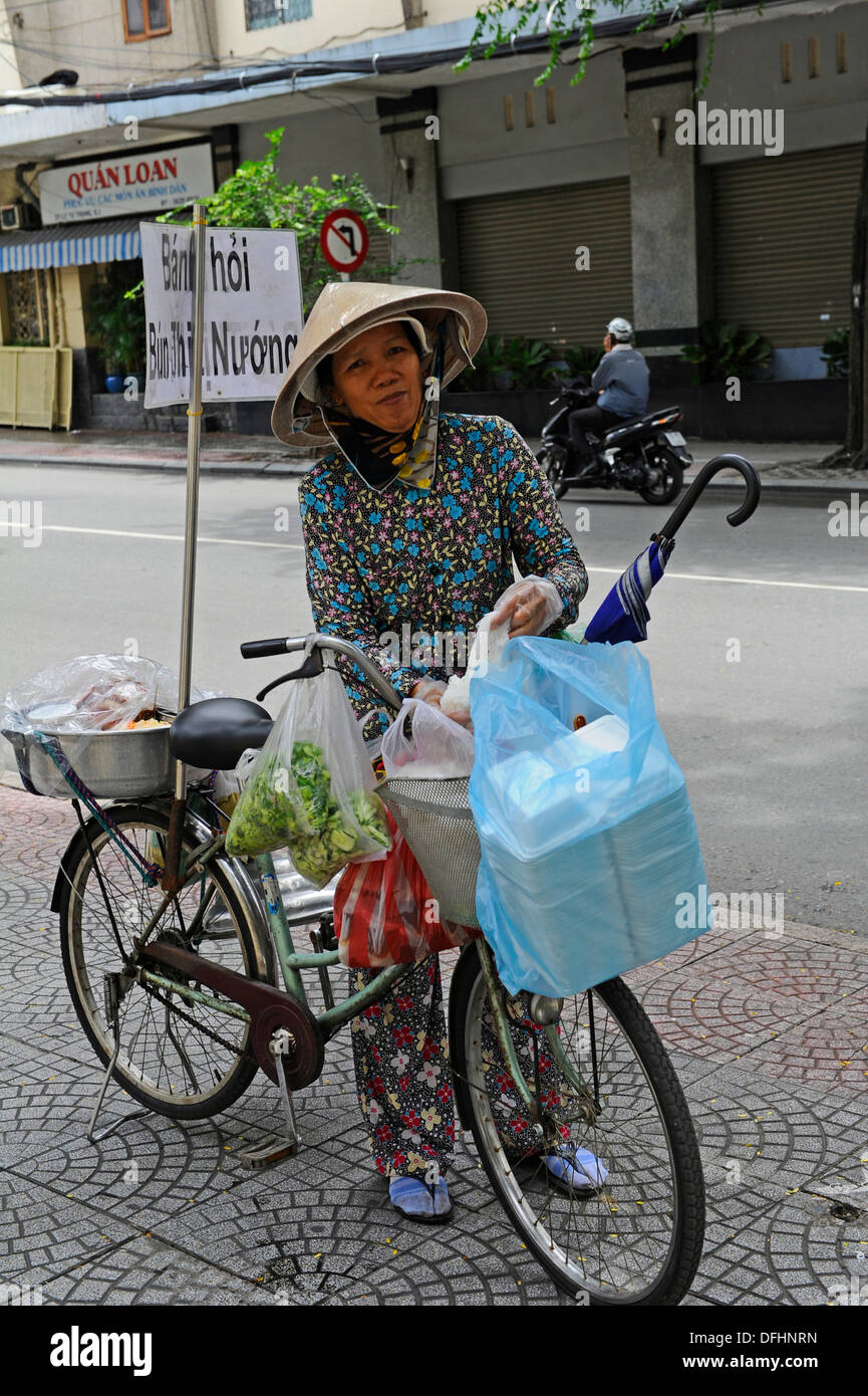Vietnamese female street trader selling food and snacks from her cycle ...
