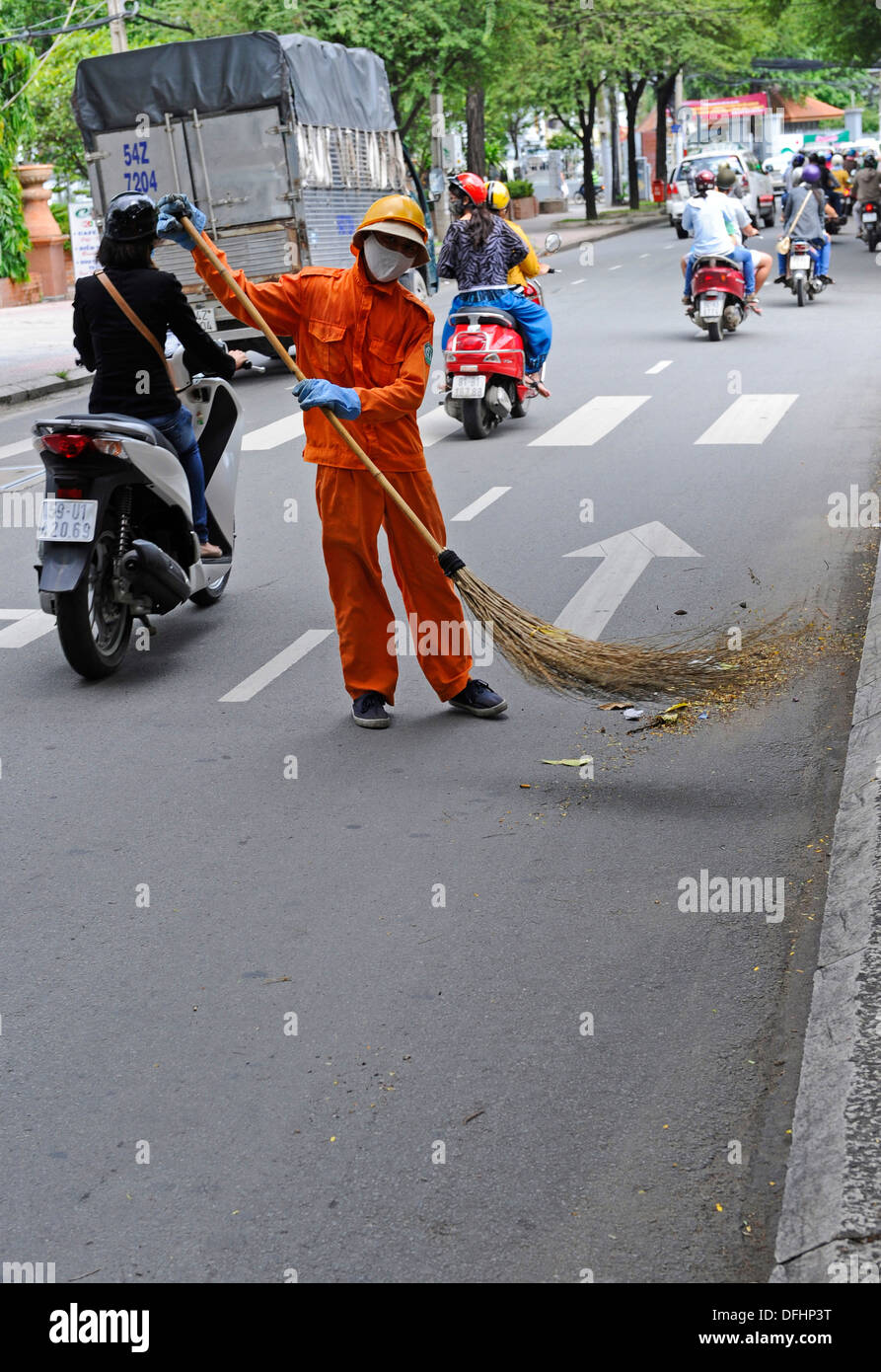 Male road sweeper on a busy road in Ho Chi Minh city sweeping the roads ...