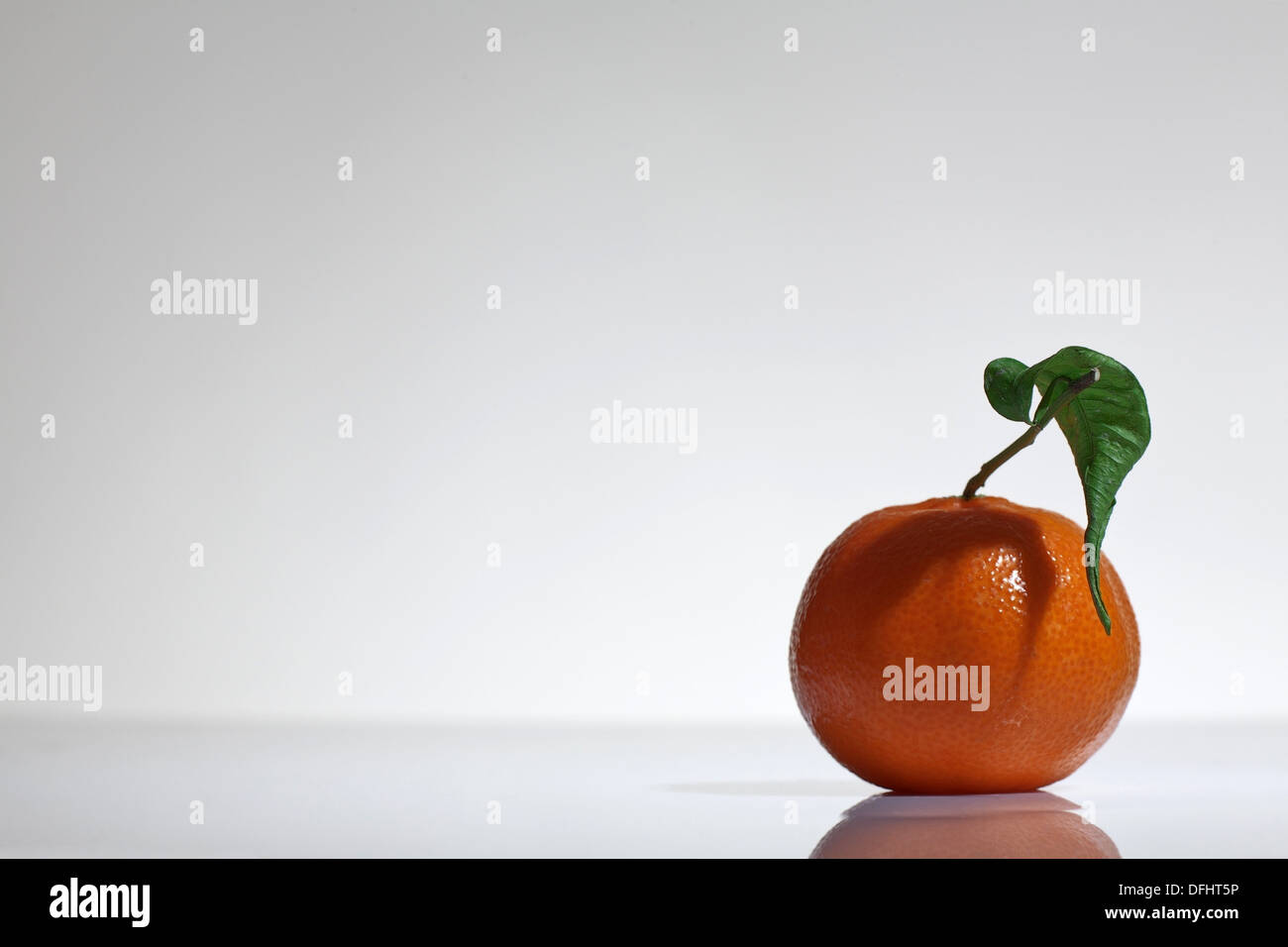 still life image of a single clementine orange on white background ...
