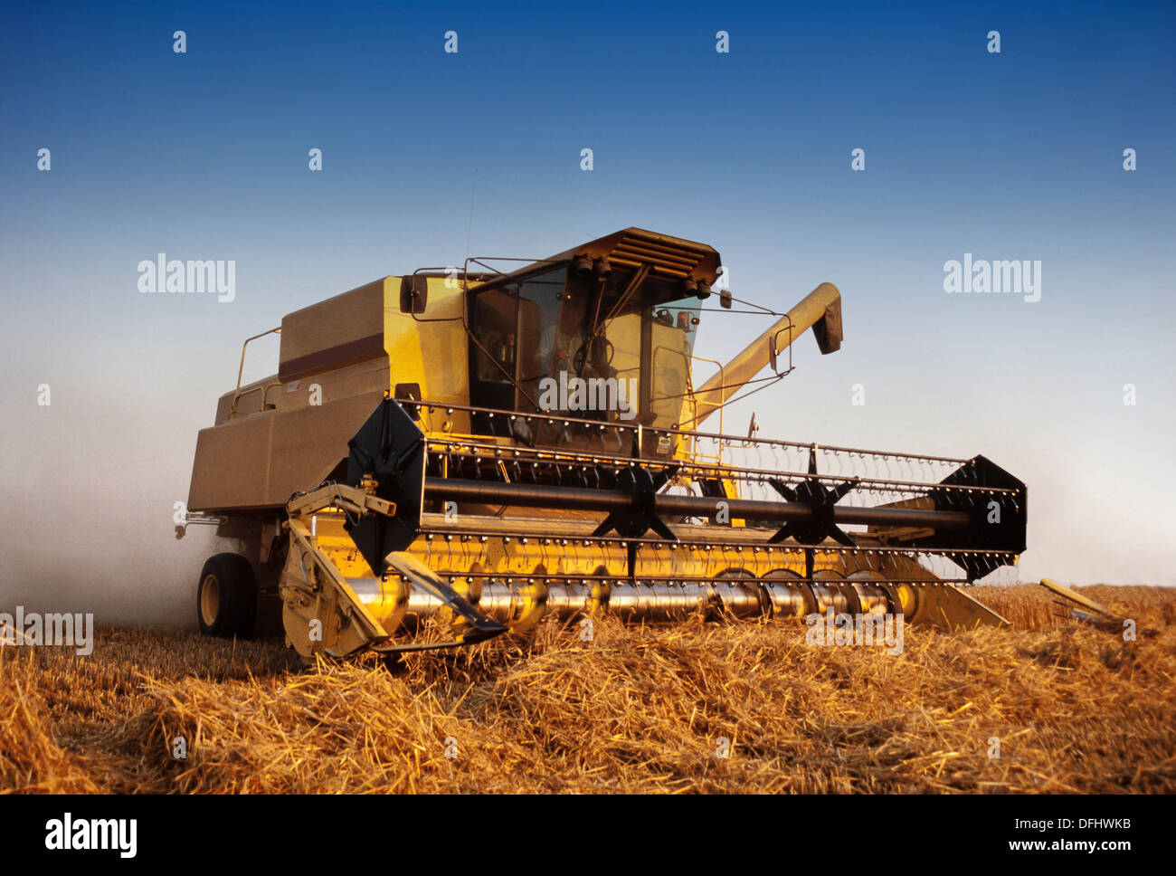 Yellow combine harvester working in field Stock Photo - Alamy