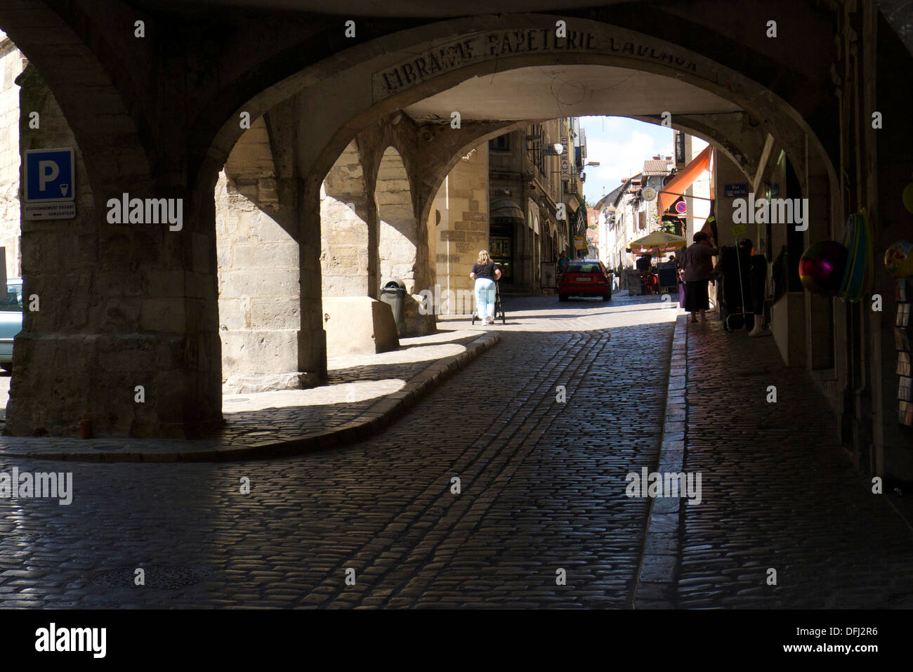 Stone archways over shadowed cobbled street, Villefranche-de-Rouergue ...