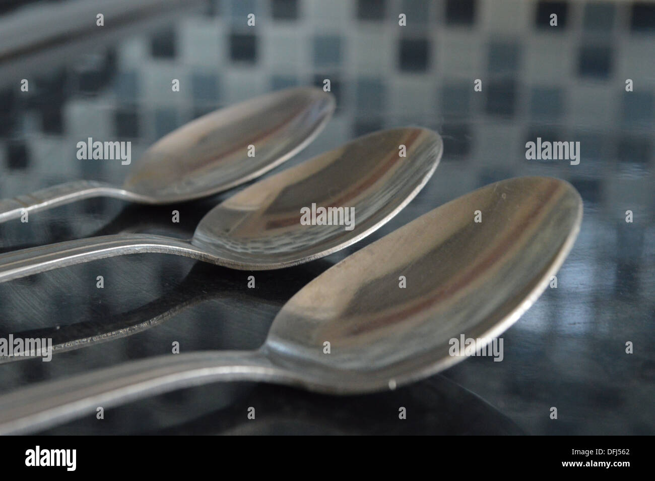 Three spoons layed out in a diagonal row with a simple background that ...