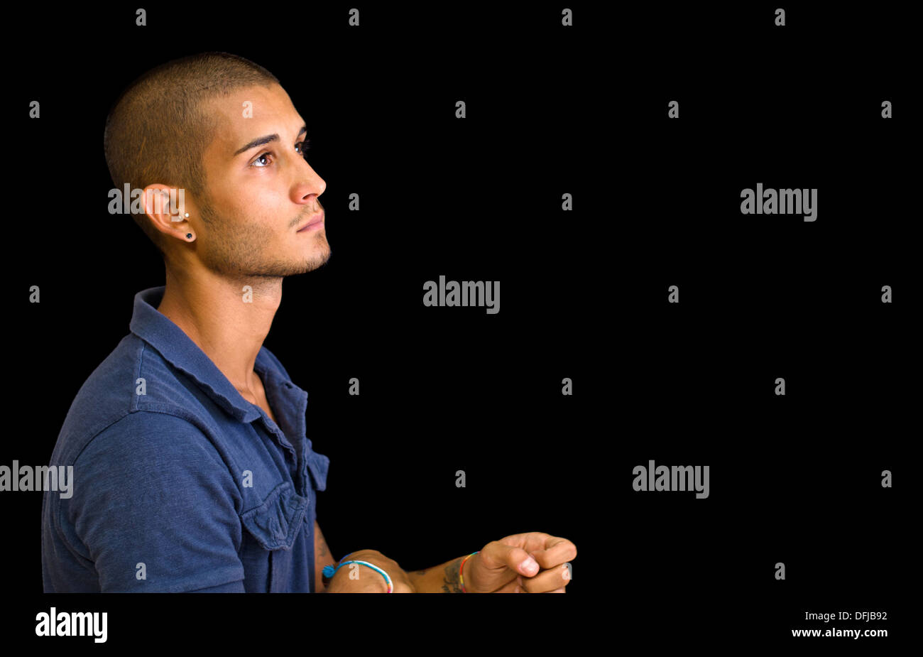 Attractive young man, side view, looking up, isolated on black ...