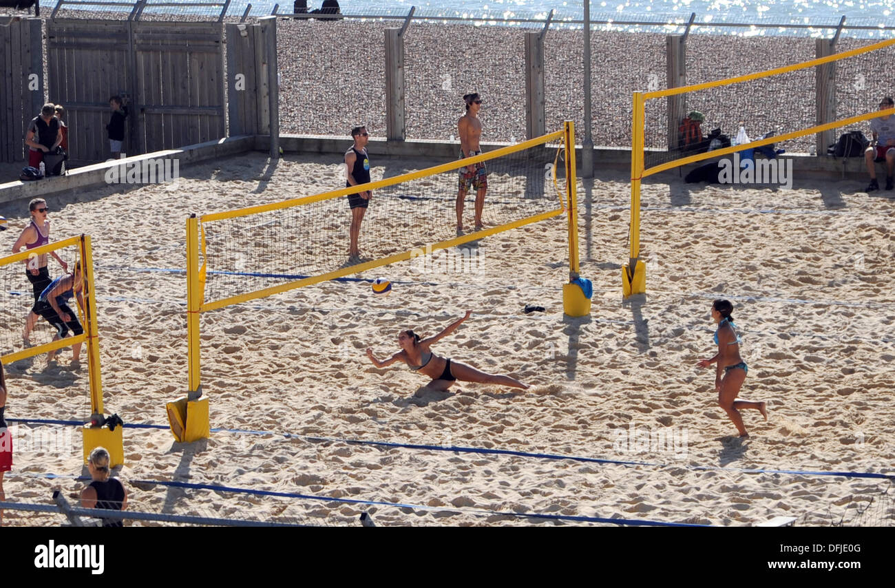 People make the most of the good weather as they play beach volleyball ...