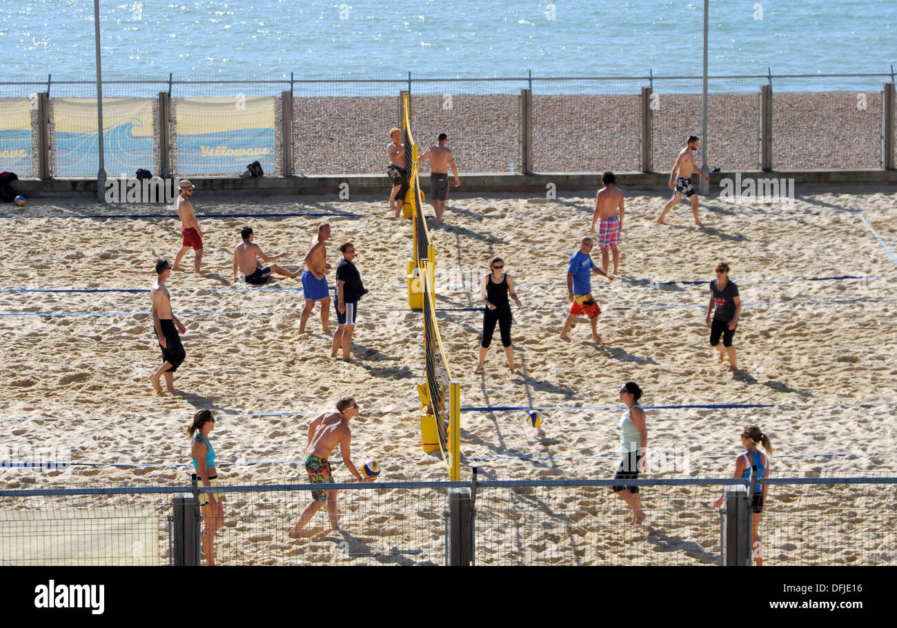 People make the most of the good weather as they play beach volleyball ...
