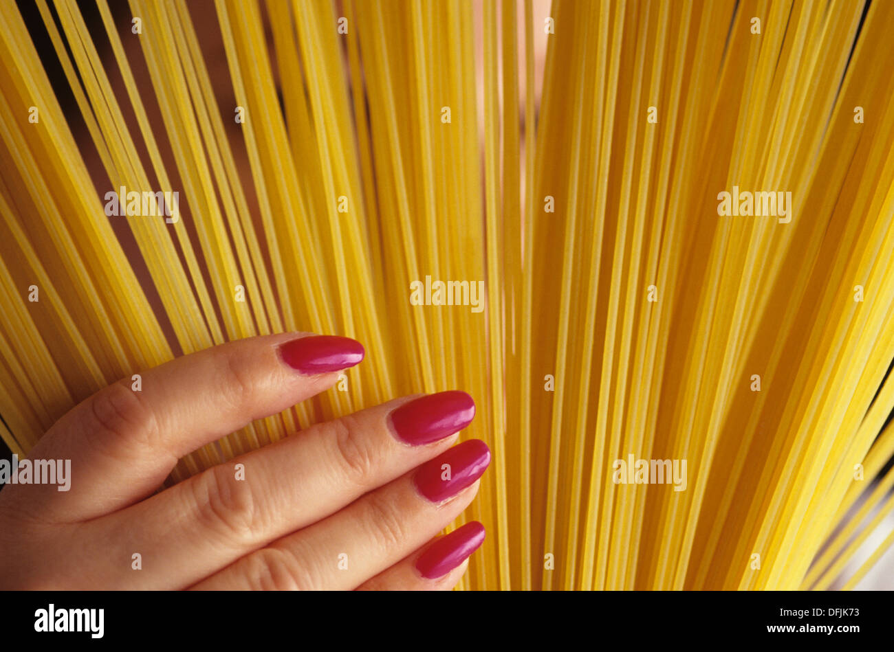 Woman's hand holding spaghetti with red nail polish Stock Photo - Alamy