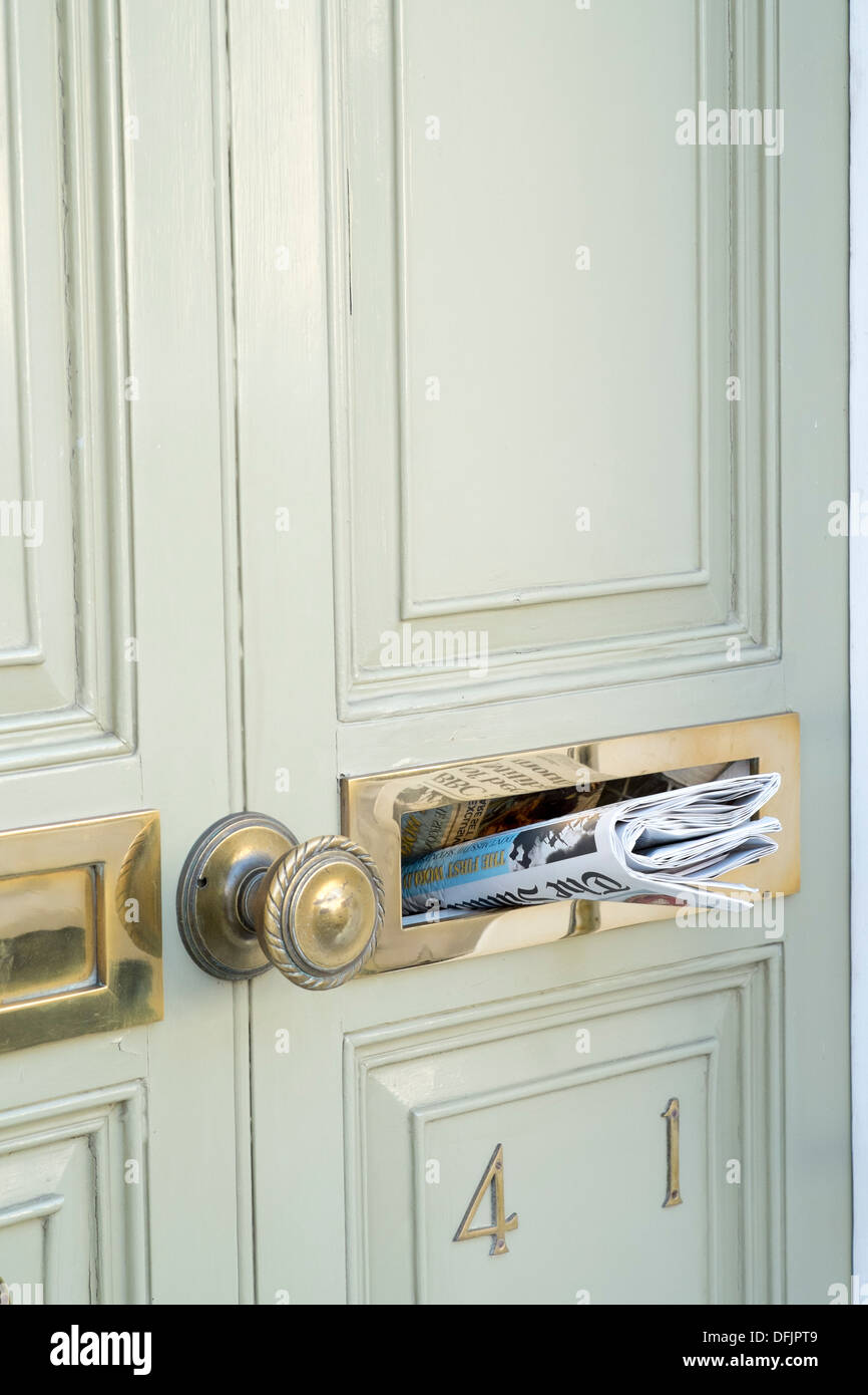 Rolled newspaper delivered into UK letter box Stock Photo - Alamy