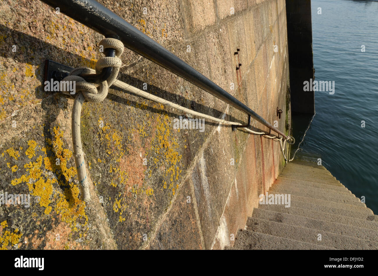 A rope going down to the sea along a stair handrail in the harbour of ...