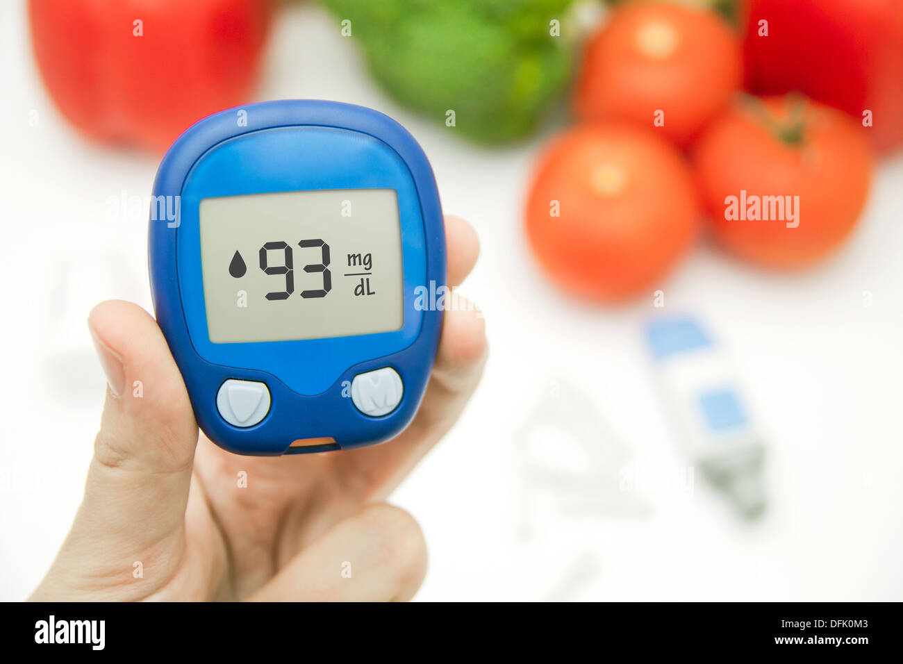 Hand holding meter. Diabetes doing glucose level test. Vegetables in ...