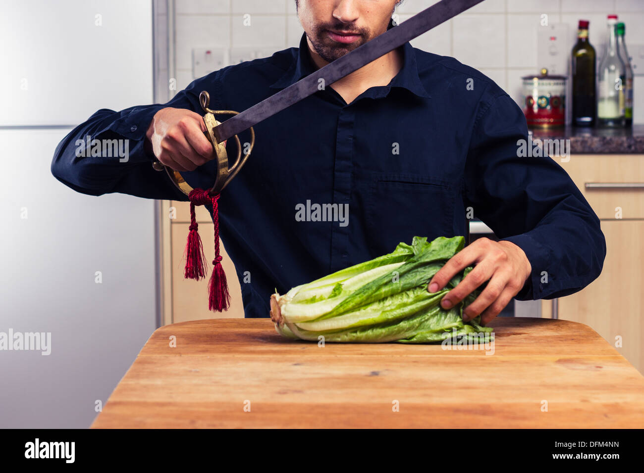 Young man cutting lettuce with a sword Stock Photo - Alamy