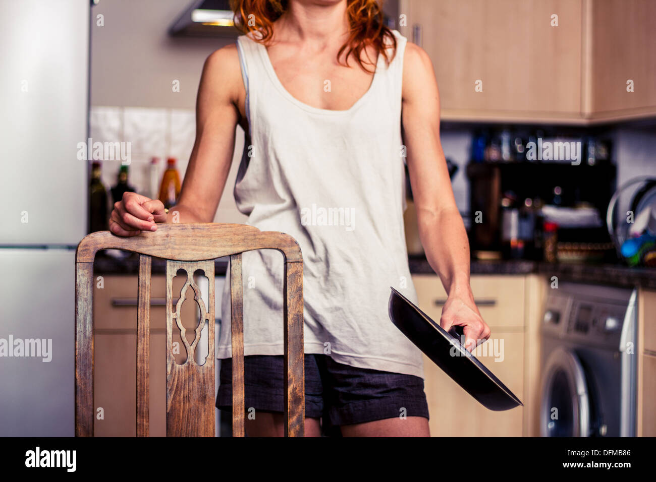 Young woman in kitchen with frying pan Stock Photo - Alamy