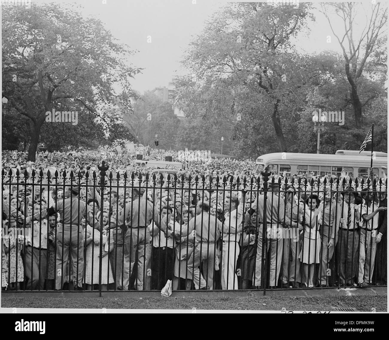 A photograph shows a large crowd gathered outside the White House gates ...