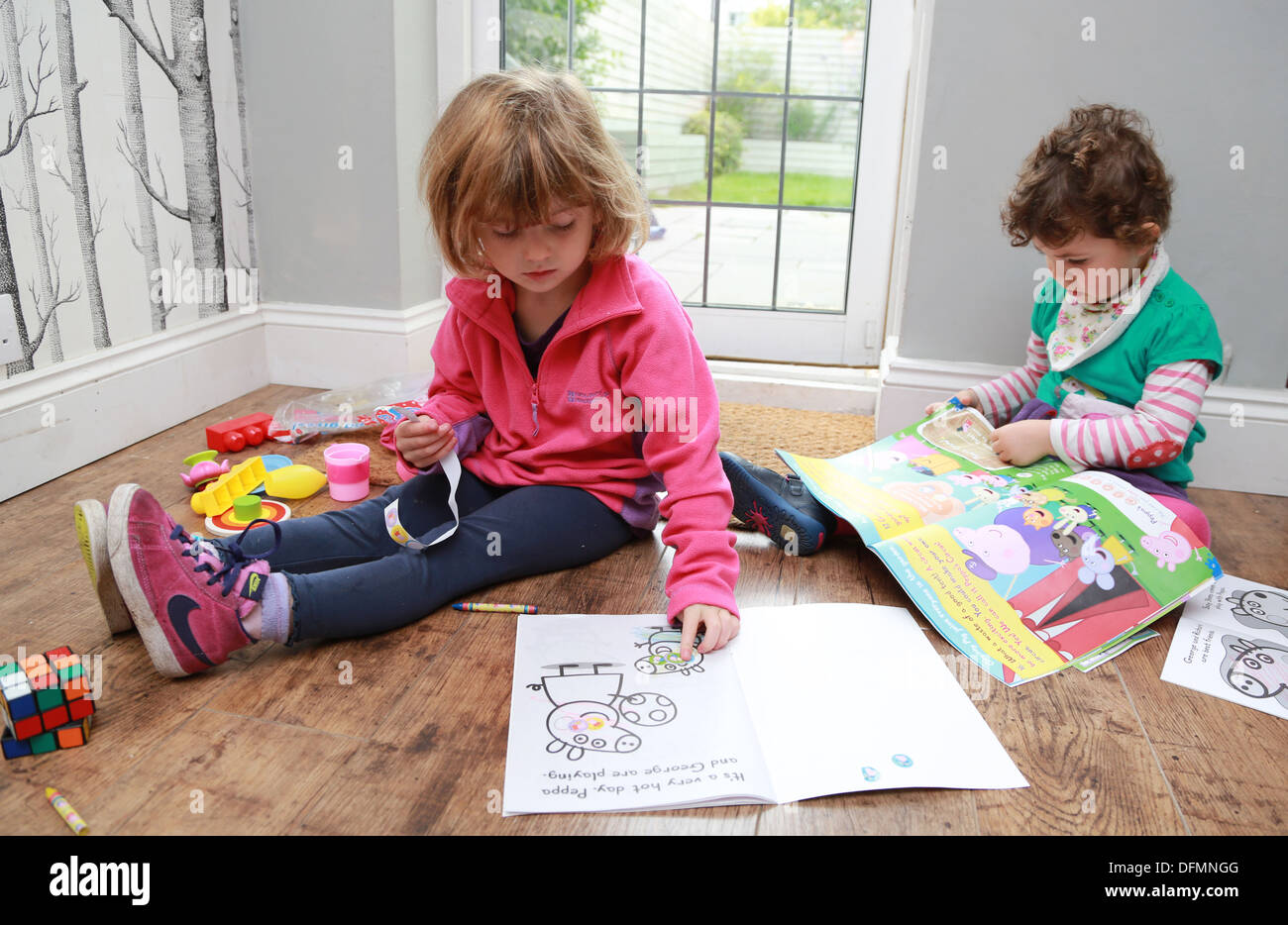 Two children sitting on the floor with activity books Stock Photo - Alamy