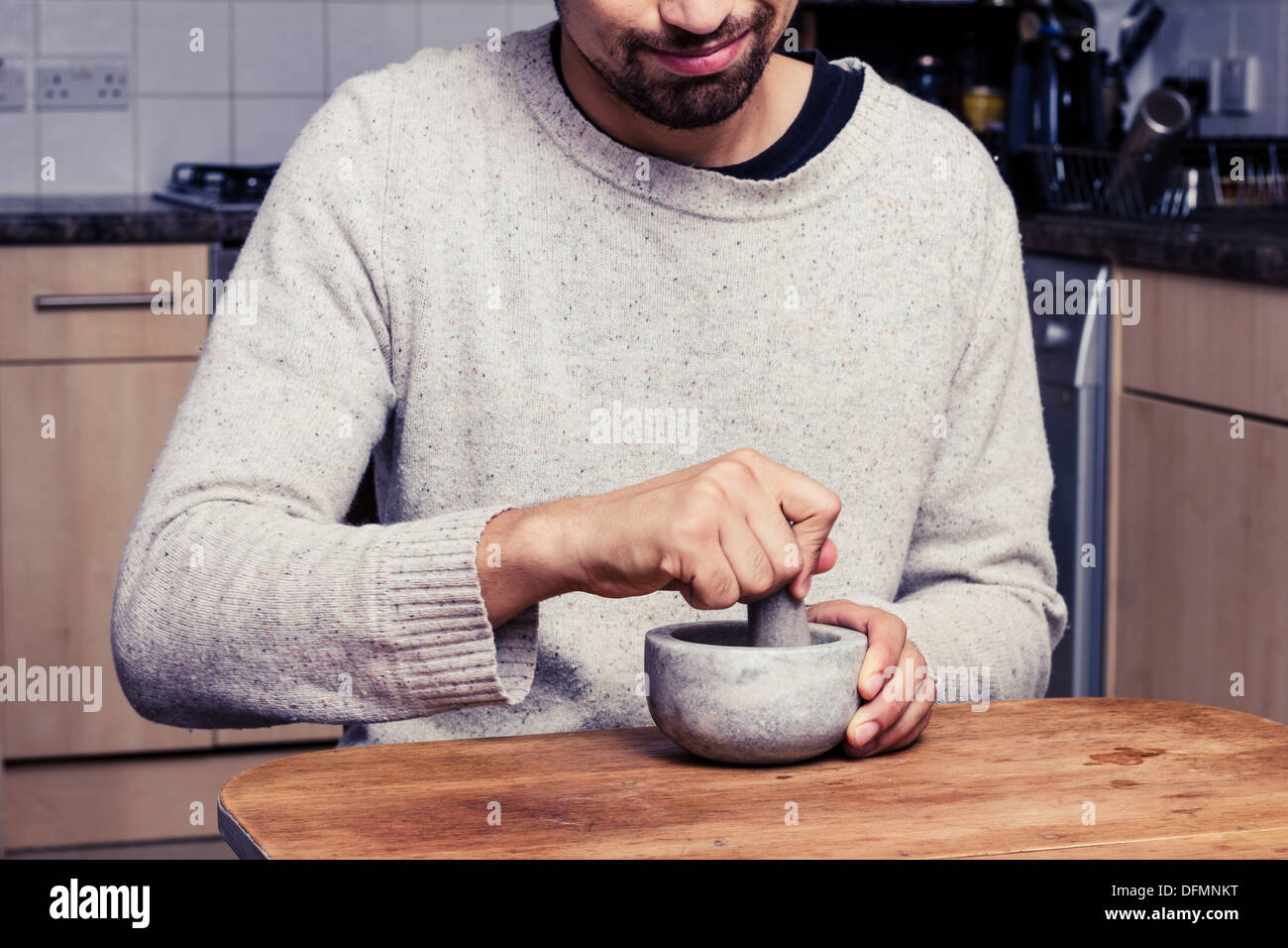 Happy young man using pestle and mortar Stock Photo - Alamy