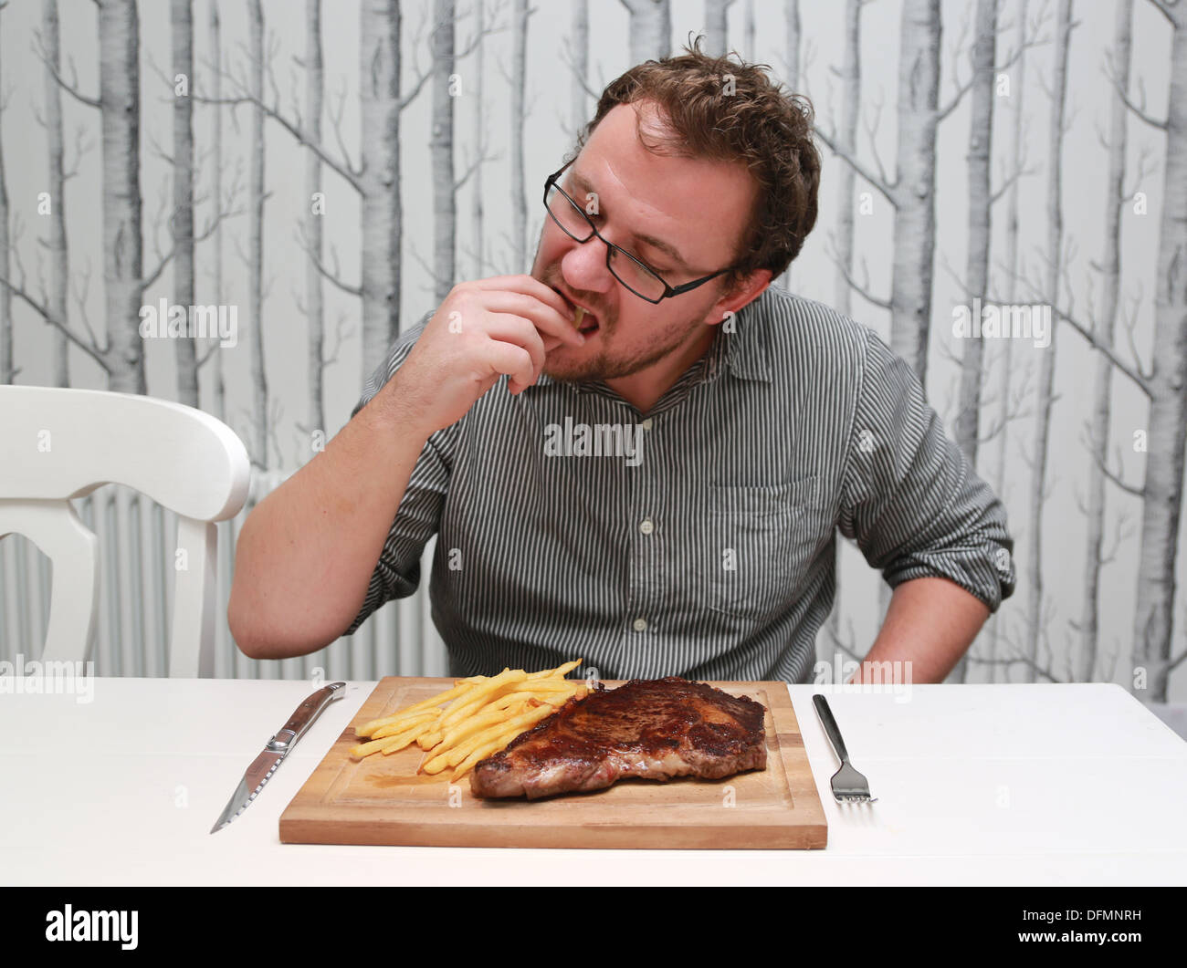 Man eating a large juicy steak with chips Stock Photo - Alamy