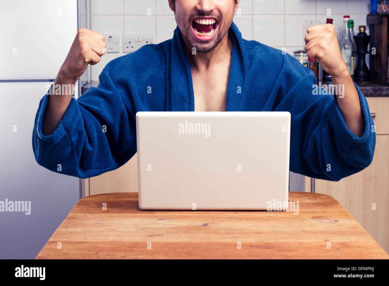 Excited young man screaming at his laptop in his kitchen Stock Photo ...