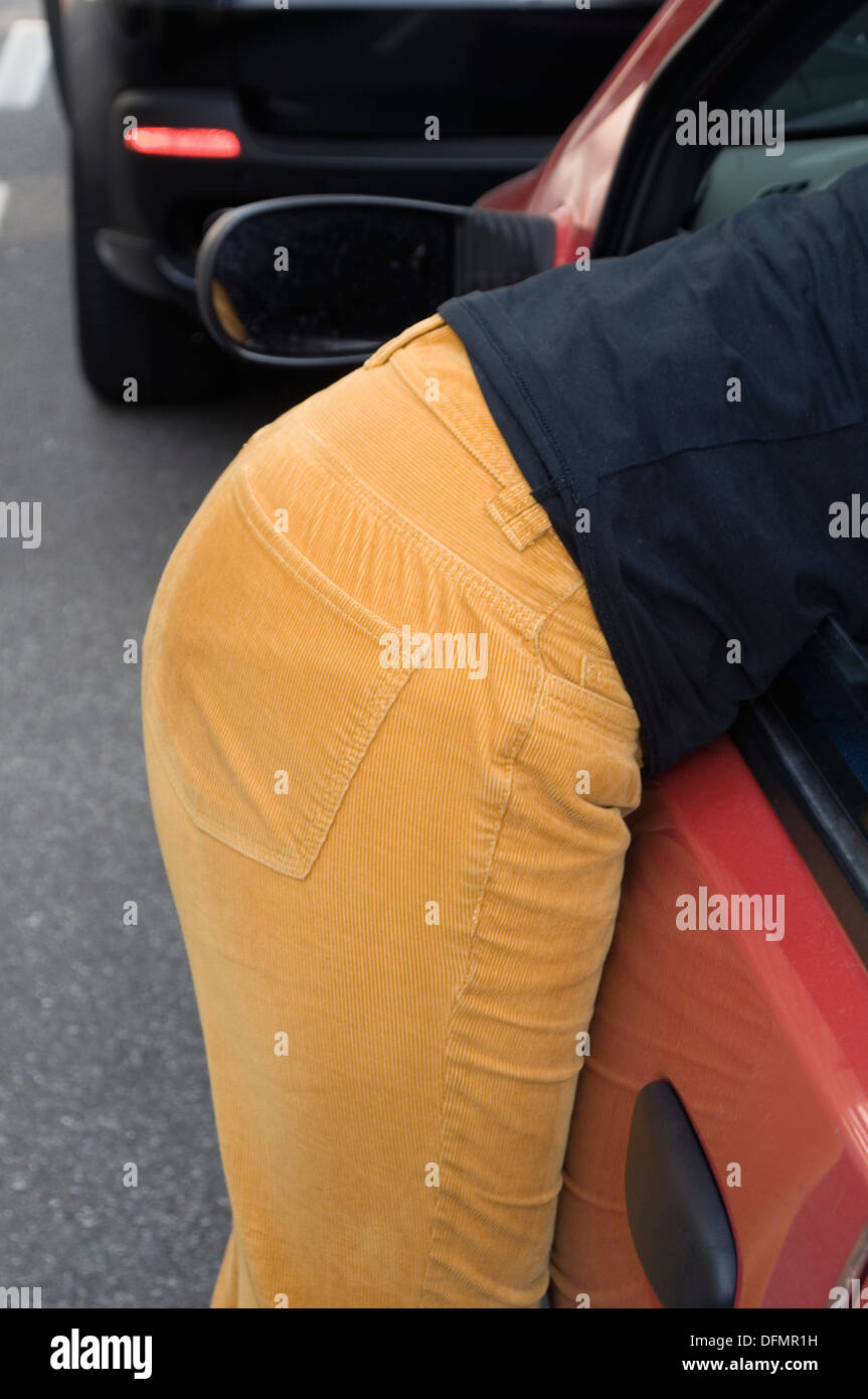 Low section of woman leaning into car Stock Photo - Alamy