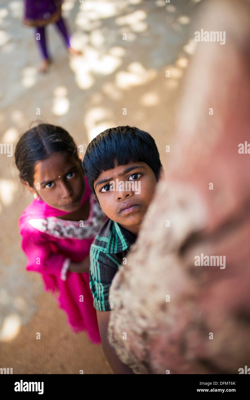 Indian boy and girl holding onto a tree in a rural indian village ...
