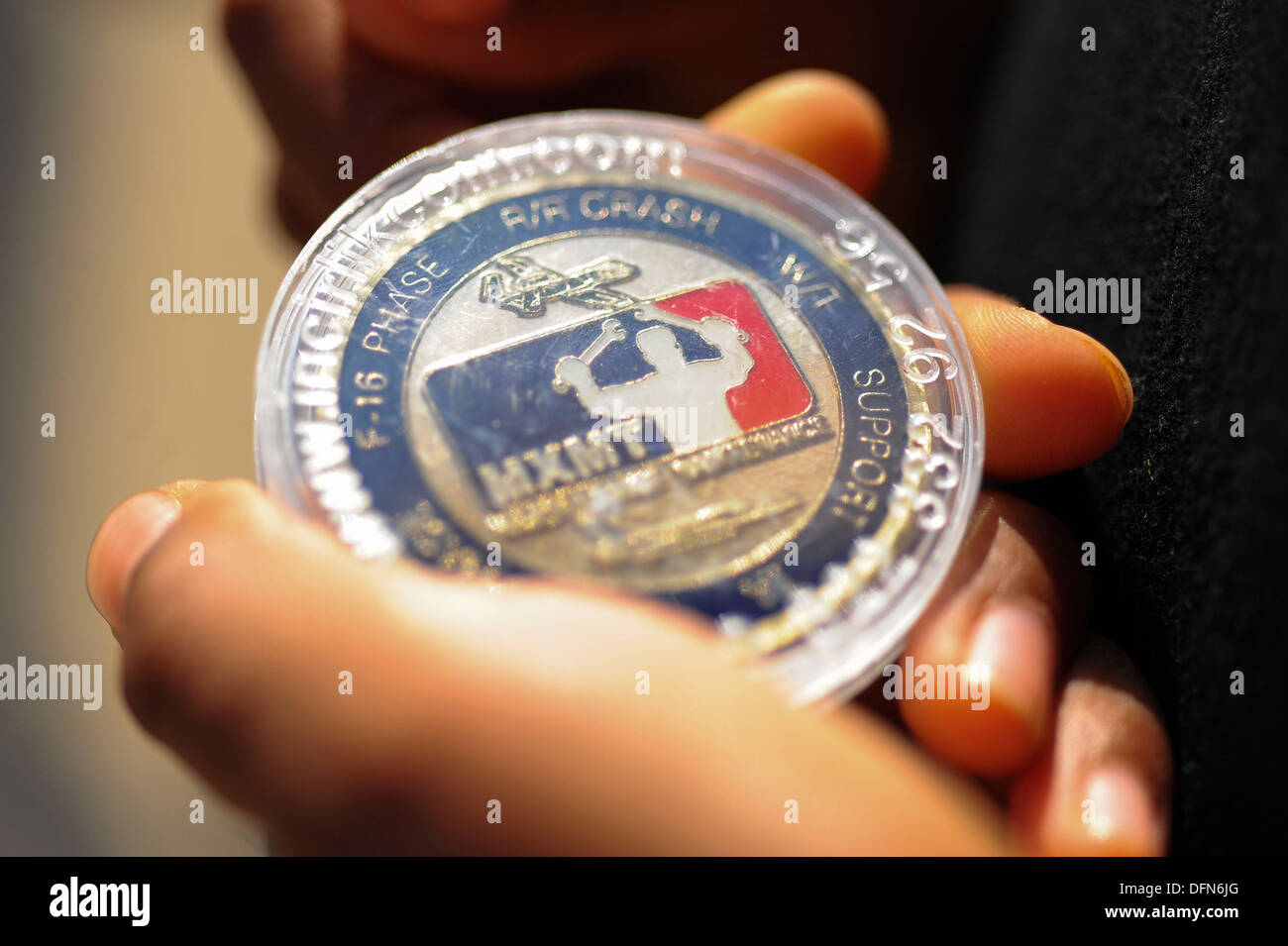 A School-Age Program child holds an Air Force Maintenance coin on the ...