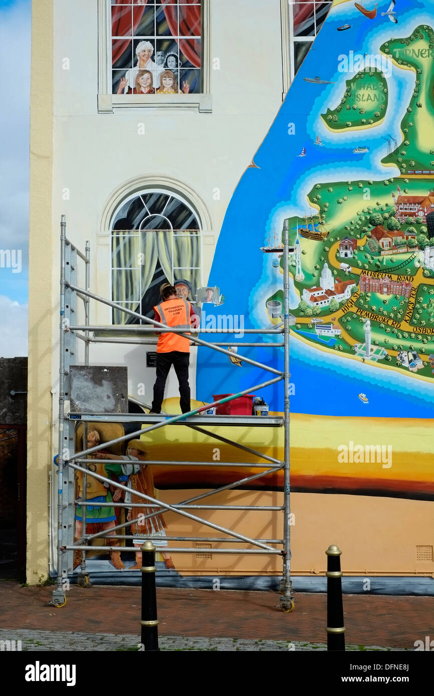 local artist painting a large artwork onto a wall depicting map of ...
