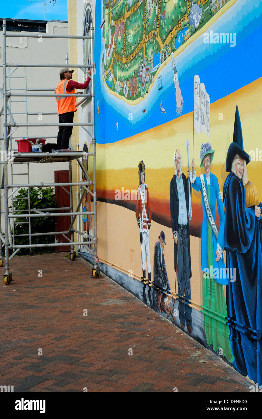 local artist painting a large artwork onto a wall depicting map of ...