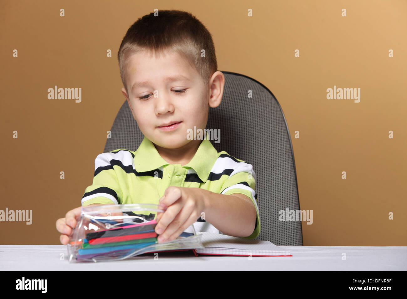 little boy child kid drawing with color pencils on brown background ...