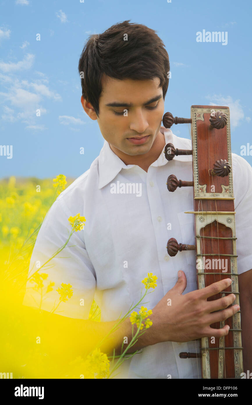 Close-up of a man playing sitar in a mustard field Stock Photo - Alamy