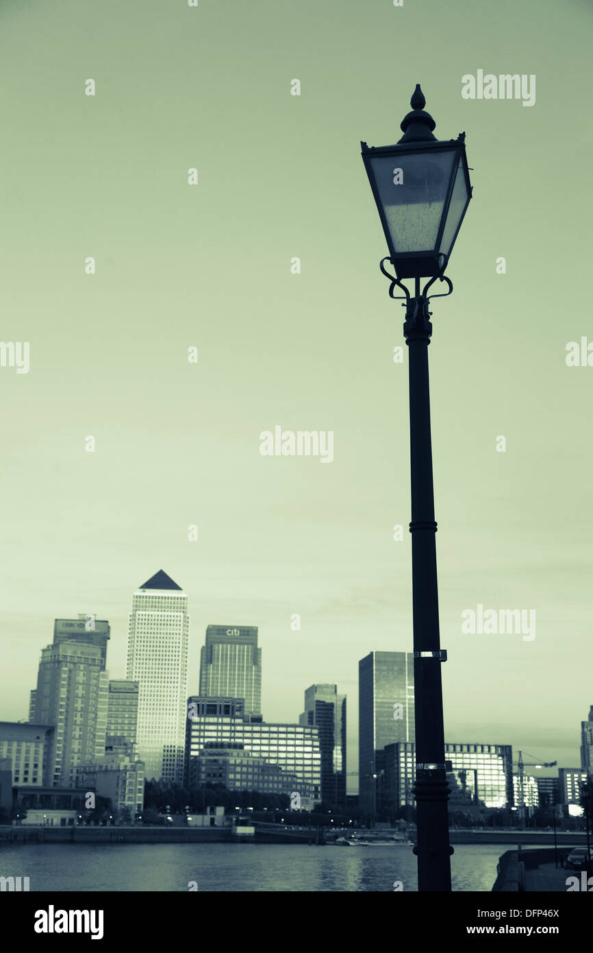 Lamp post in foreground, canary wharf in background with golden sun ...