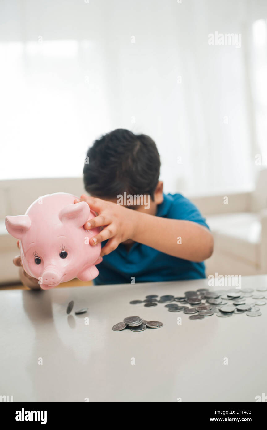 Boy taking out coins from a piggy bank Stock Photo - Alamy