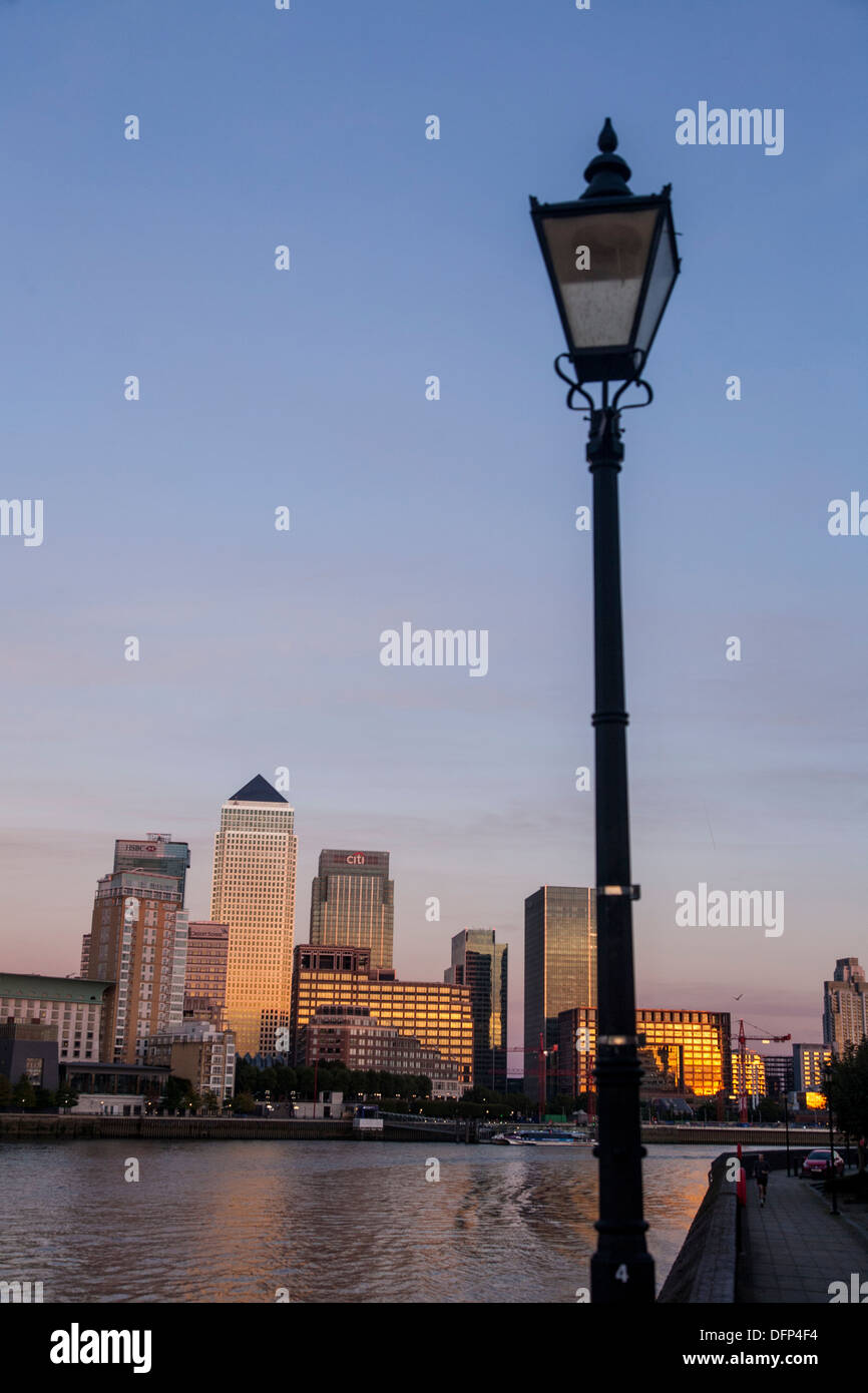 Lamp post in foreground, canary wharf in background with golden sun ...