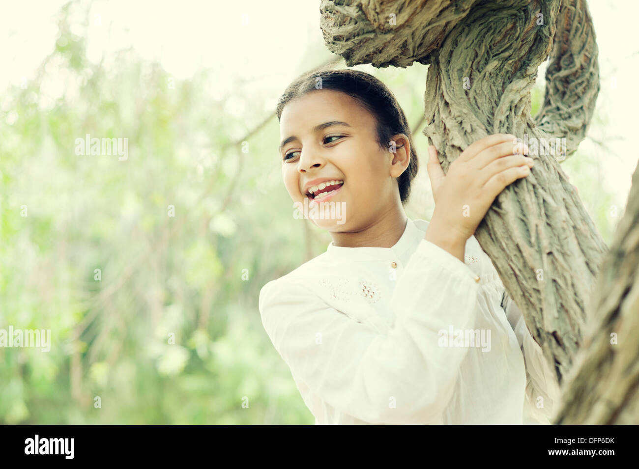 Girl playing on a tree in a park Stock Photo - Alamy