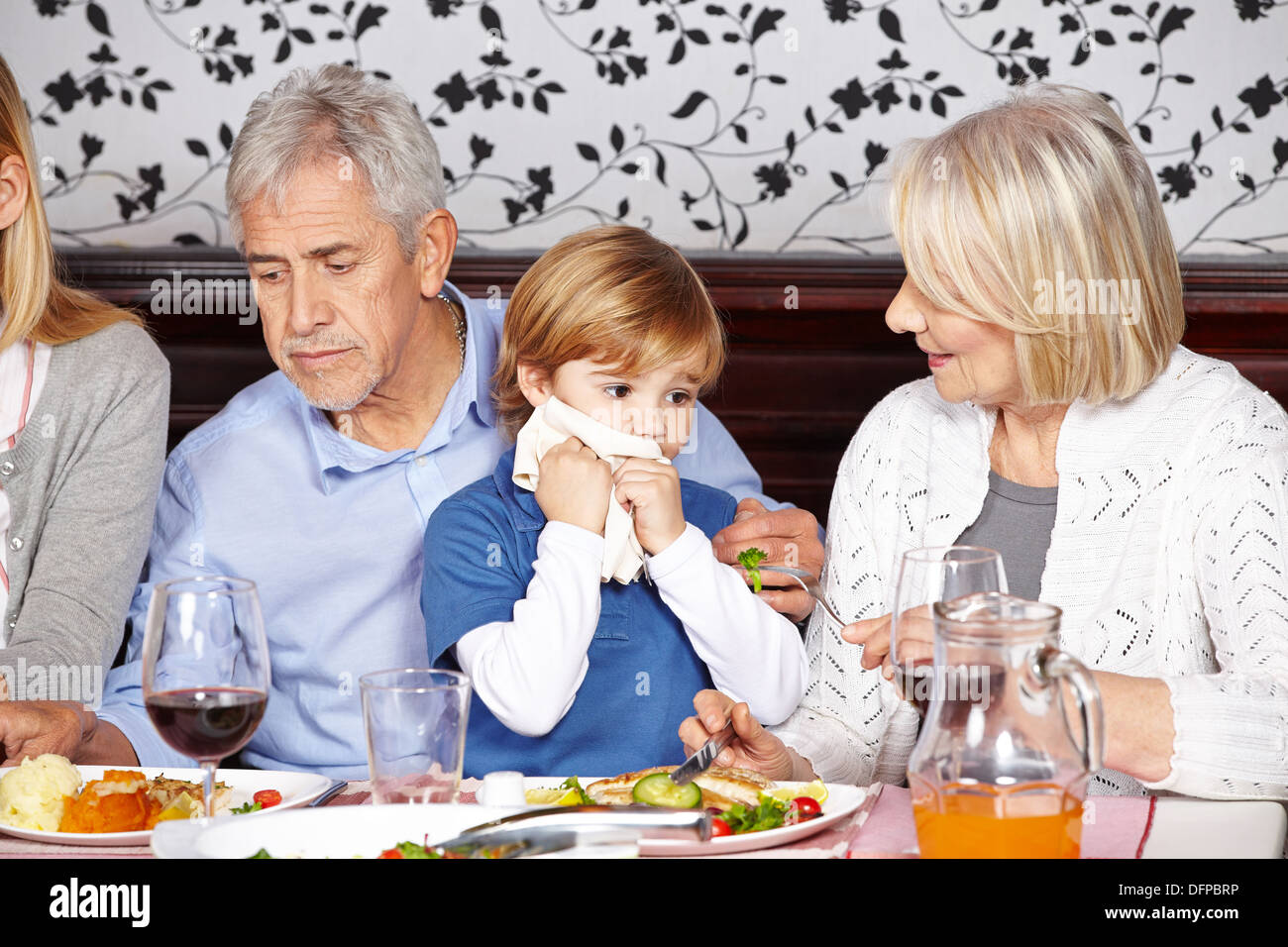 Child cleaning mouth with napkin at family dinner Stock Photo - Alamy