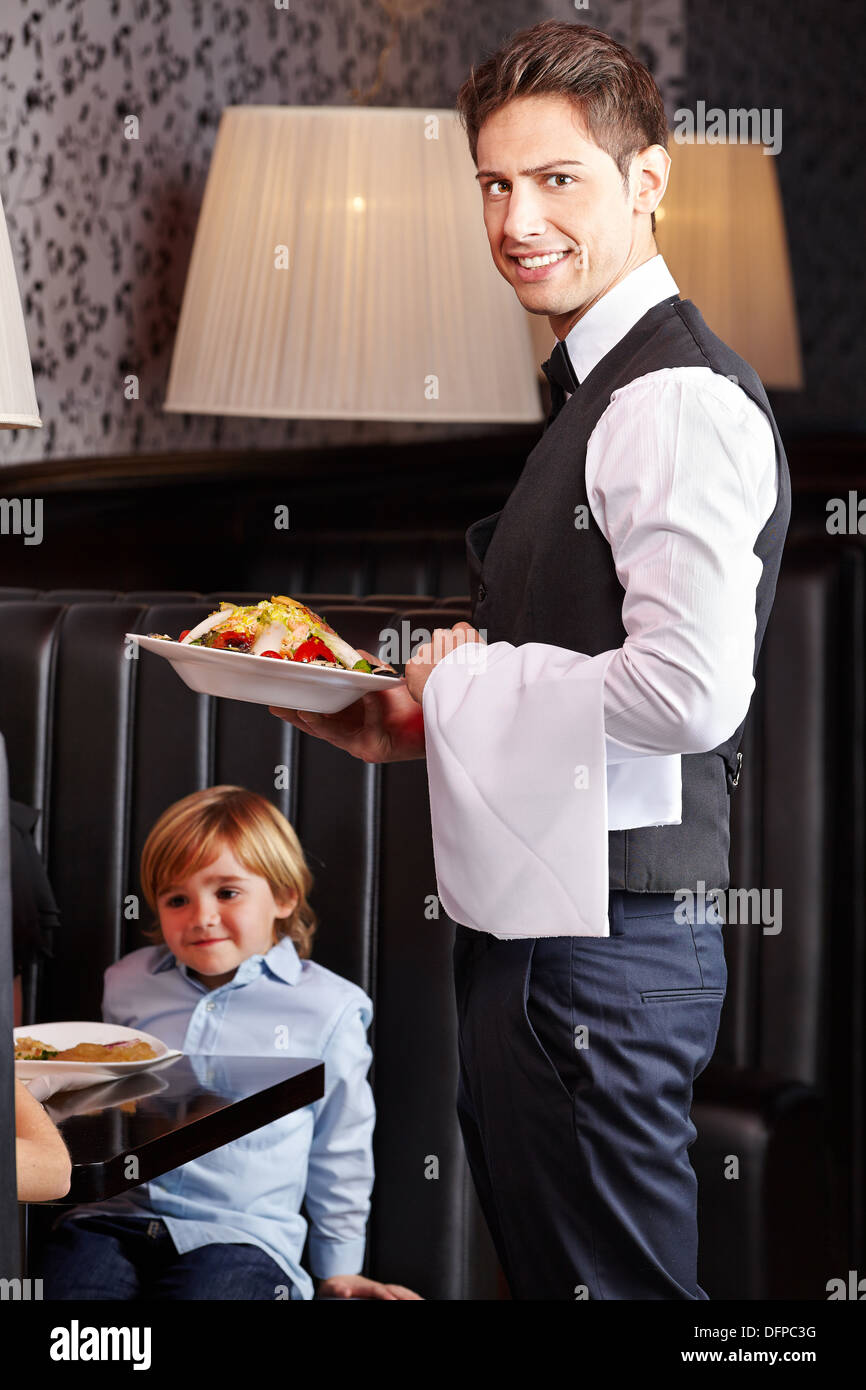 Happy waiter serving salad food in a restaurant Stock Photo - Alamy