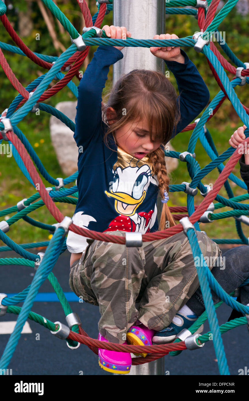 Little girl Climbing Up A Rope Climbing Frame At A Childrens Playground ...