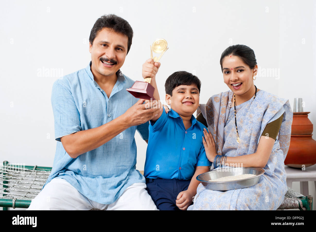 Portrait of a couple with their son holding a winning trophy Stock ...
